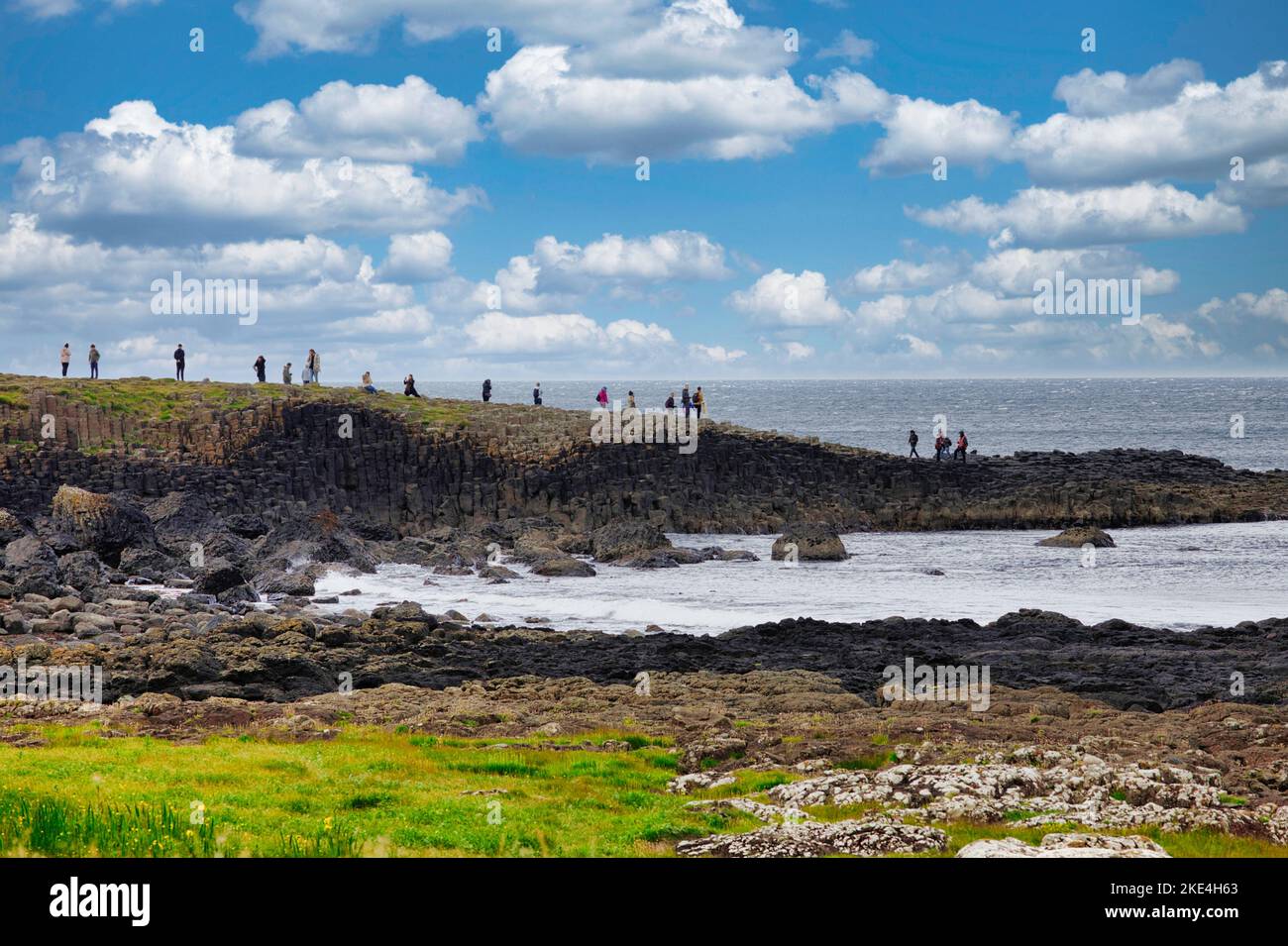 Tourists climbing on the ancient basalt colums of the Giant's Causeway ...