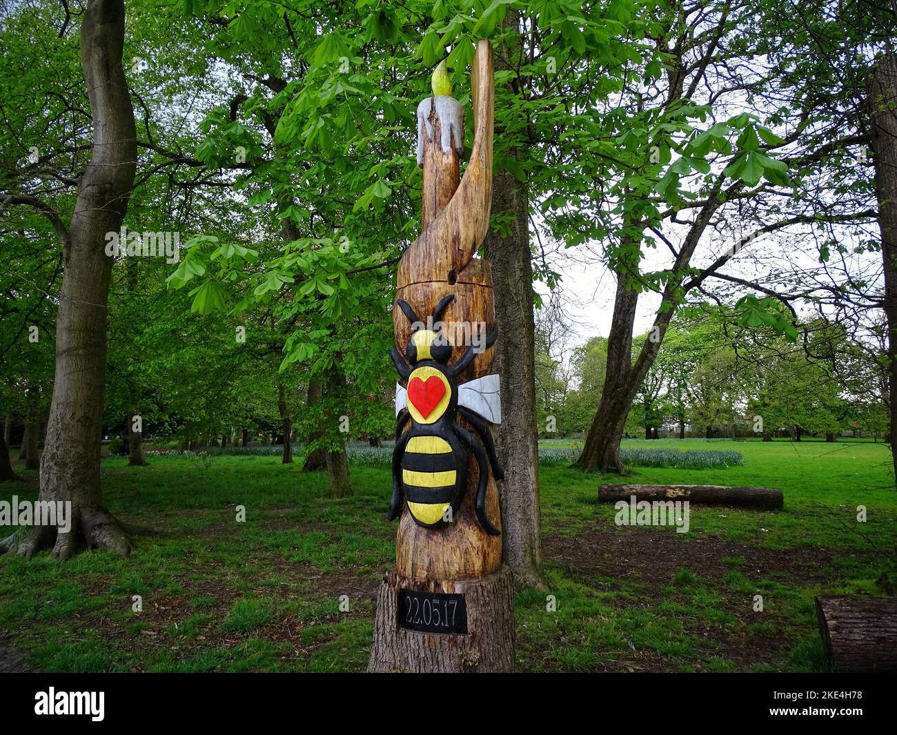 Wood carved statue of the bee with green trees in the park in the ...