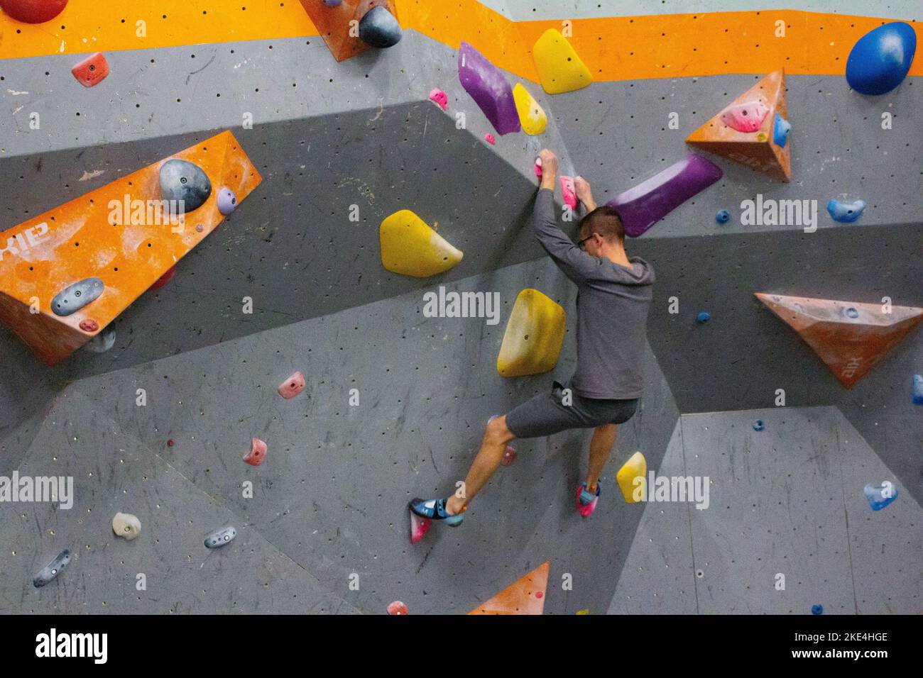 A handsome rock-climber bouldering on colorful slopers on the climbing wall in the gym Stock ...