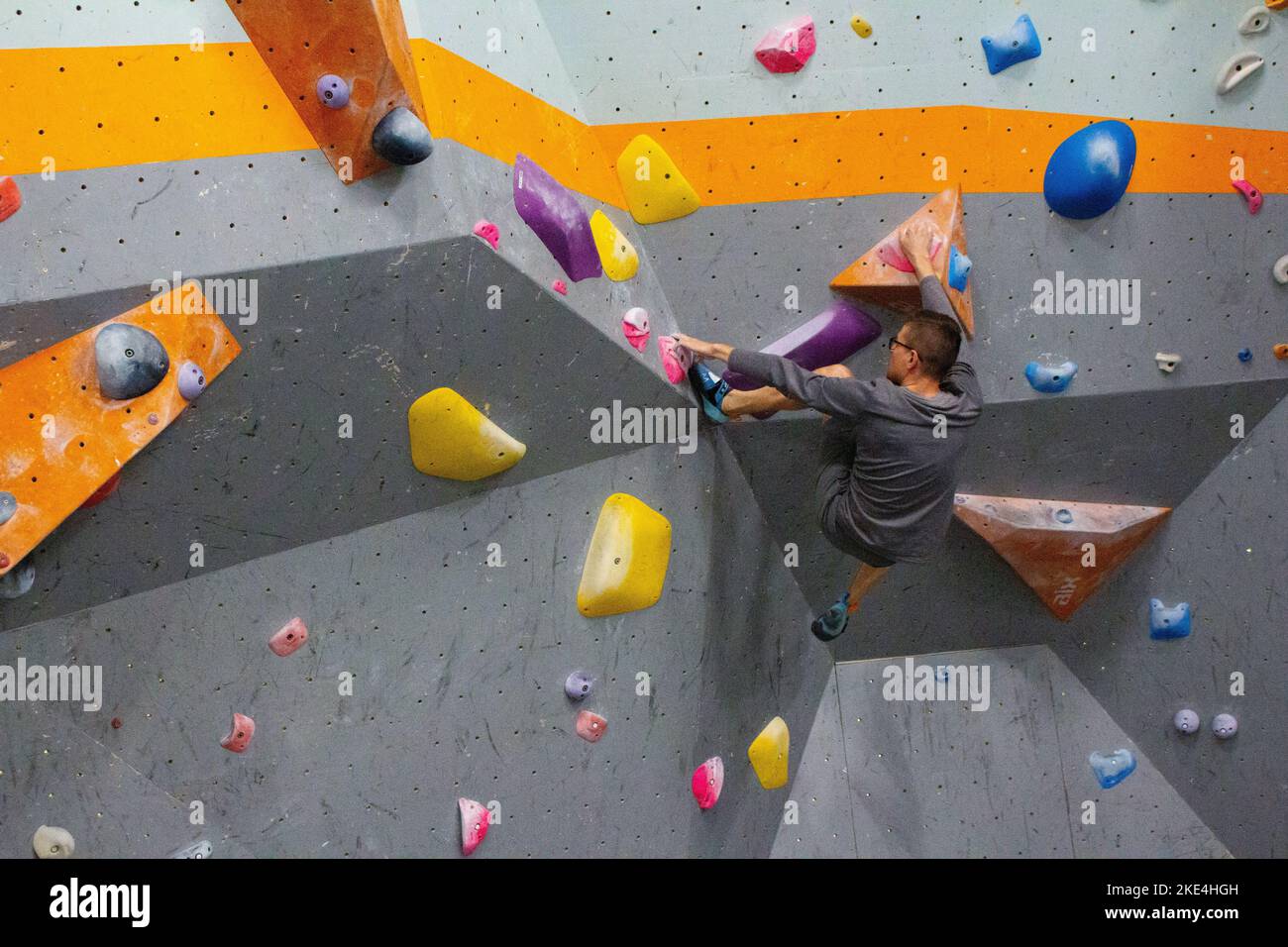 A handsome rock-climber male bouldering on colorful slopers on the ...