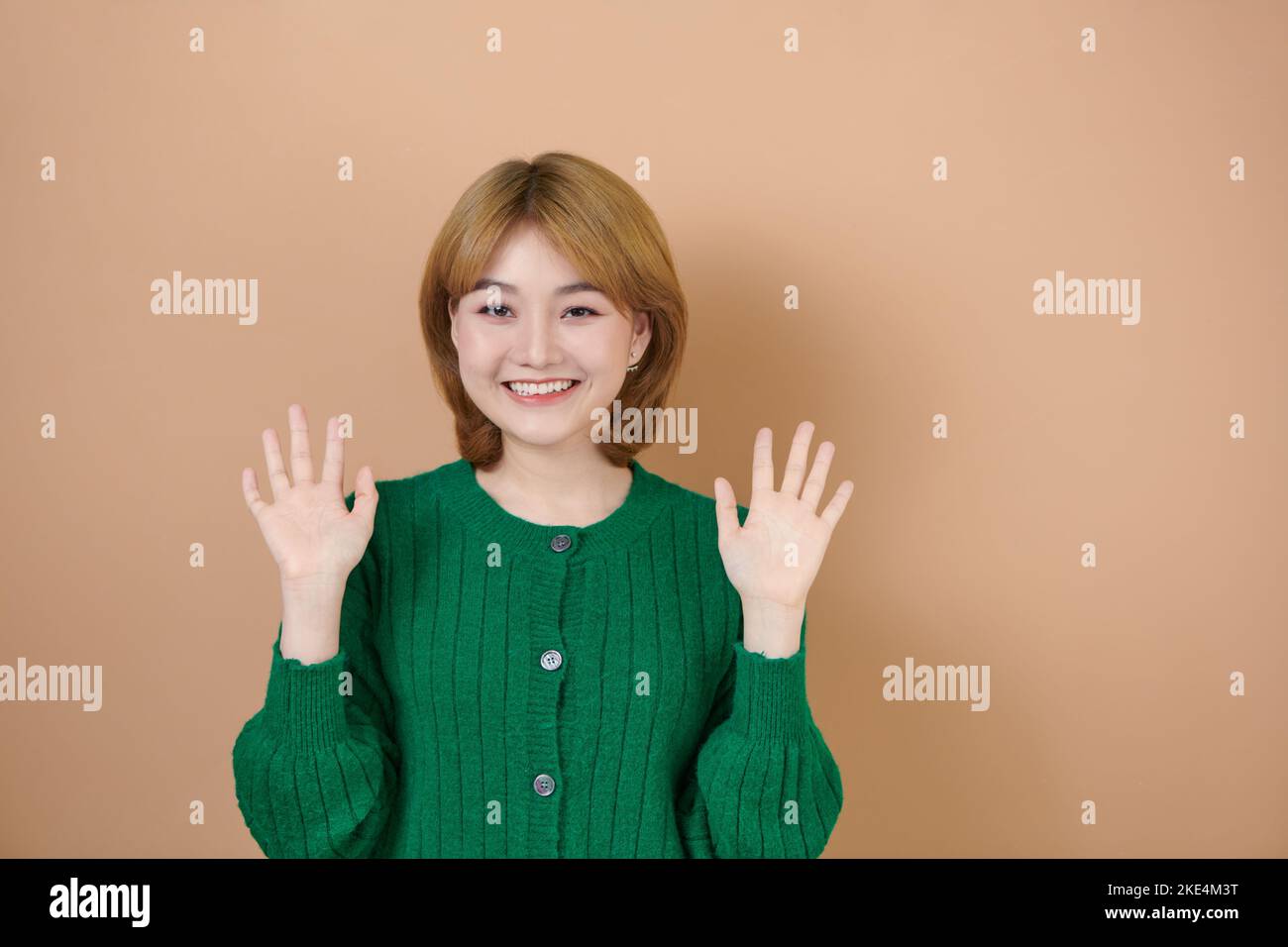 Portrait of friendly positive young woman smiles toothily, raises palms ...