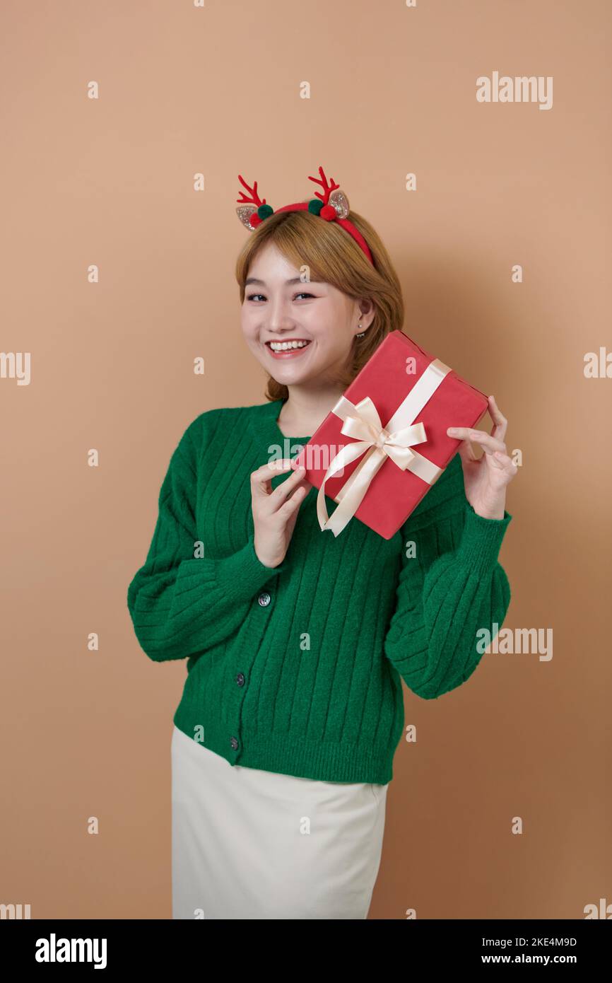 Happy girl wearing Christmas deer horns holding a gift box wrapped in ...
