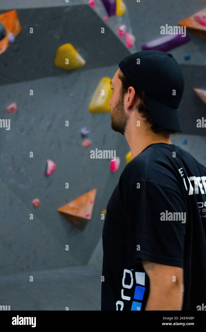 A handsome rock climber standing in front of the climbing wall with ...