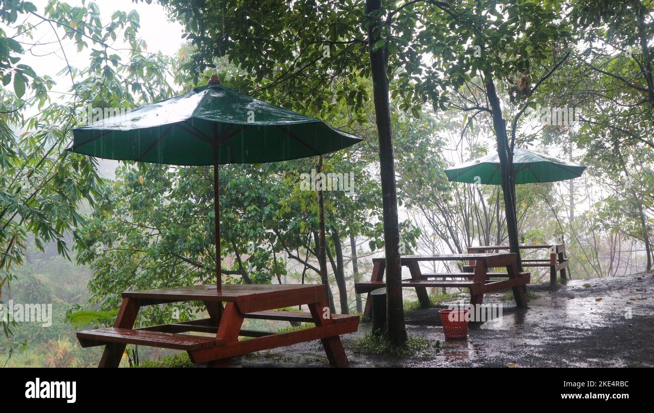 Wooden table with umbrella in the rain Stock Photo - Alamy