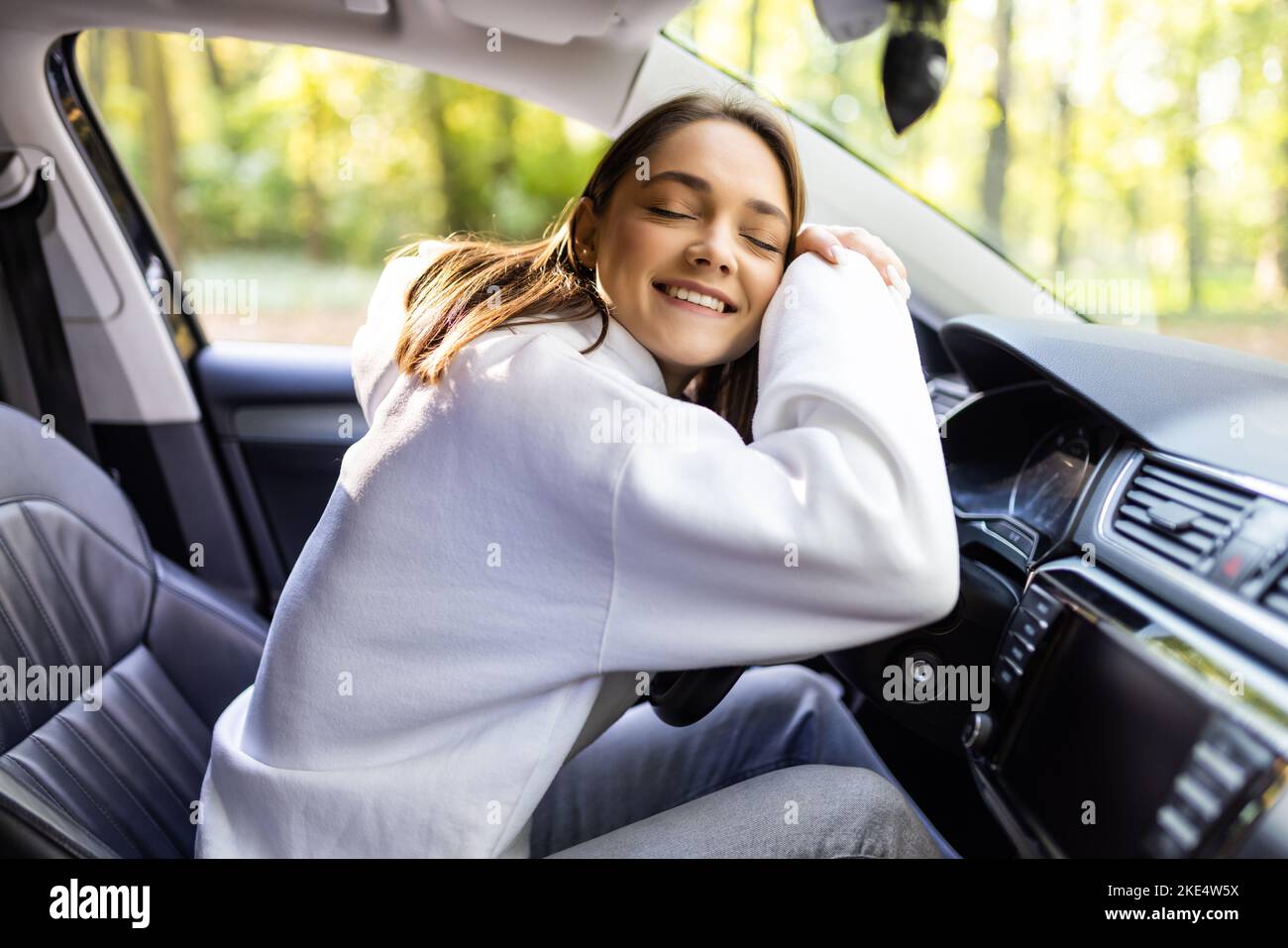 Portrait of a beautiful teenage girl smiling while holding the steering ...