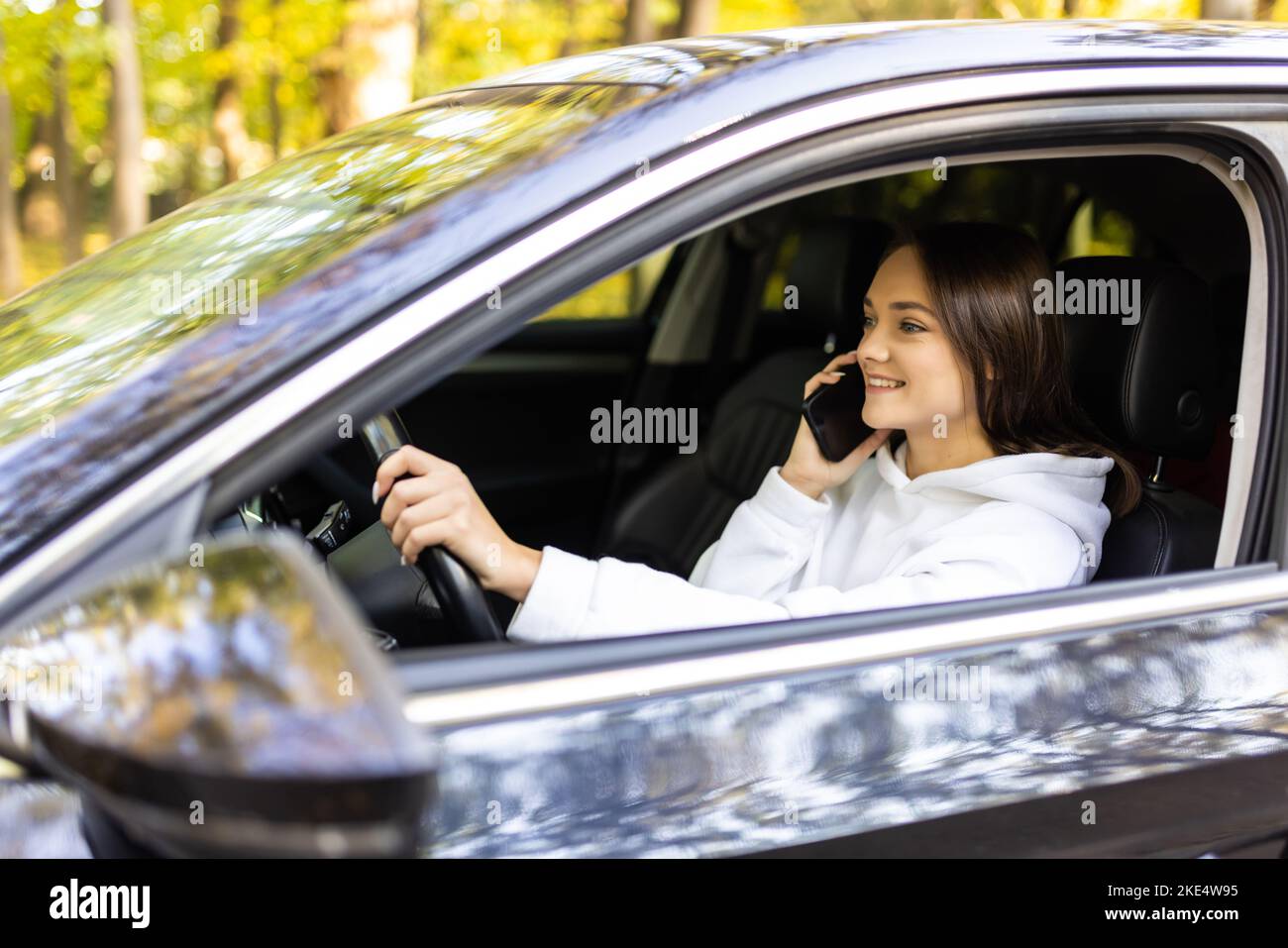Driver Woman Driving A Car Distracted On The Phone And Looking At Side