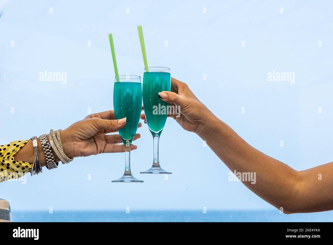 Two hands cheering with blue cocktails outdoors Stock Photo - Alamy