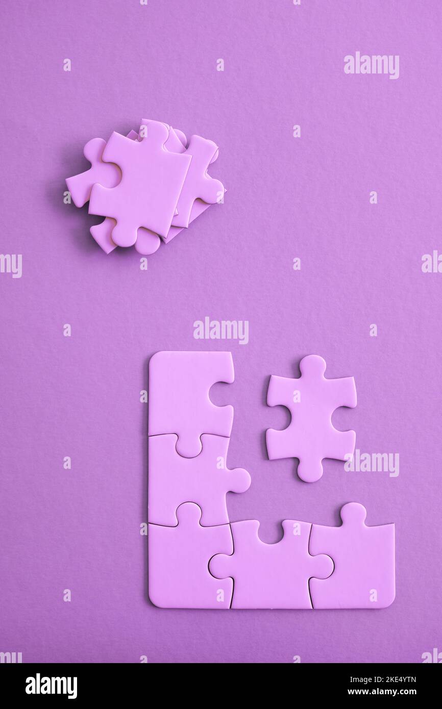 Purple jigsaw puzzle pieces on purple backgroun with pieces piled and ...