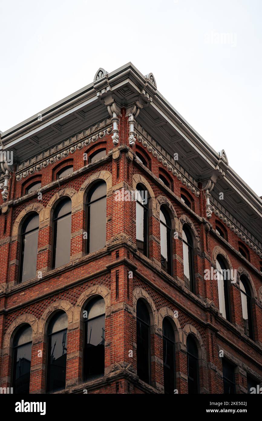 A vertical view of a red-tiled building with arc-shaped windows and a ...