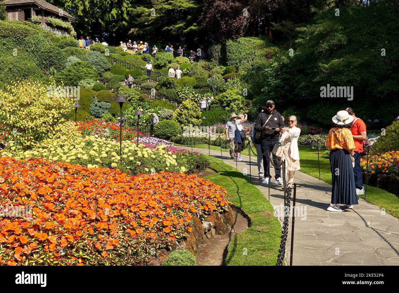 Tourists walking on the path down to a famous sunken garden and taking ...