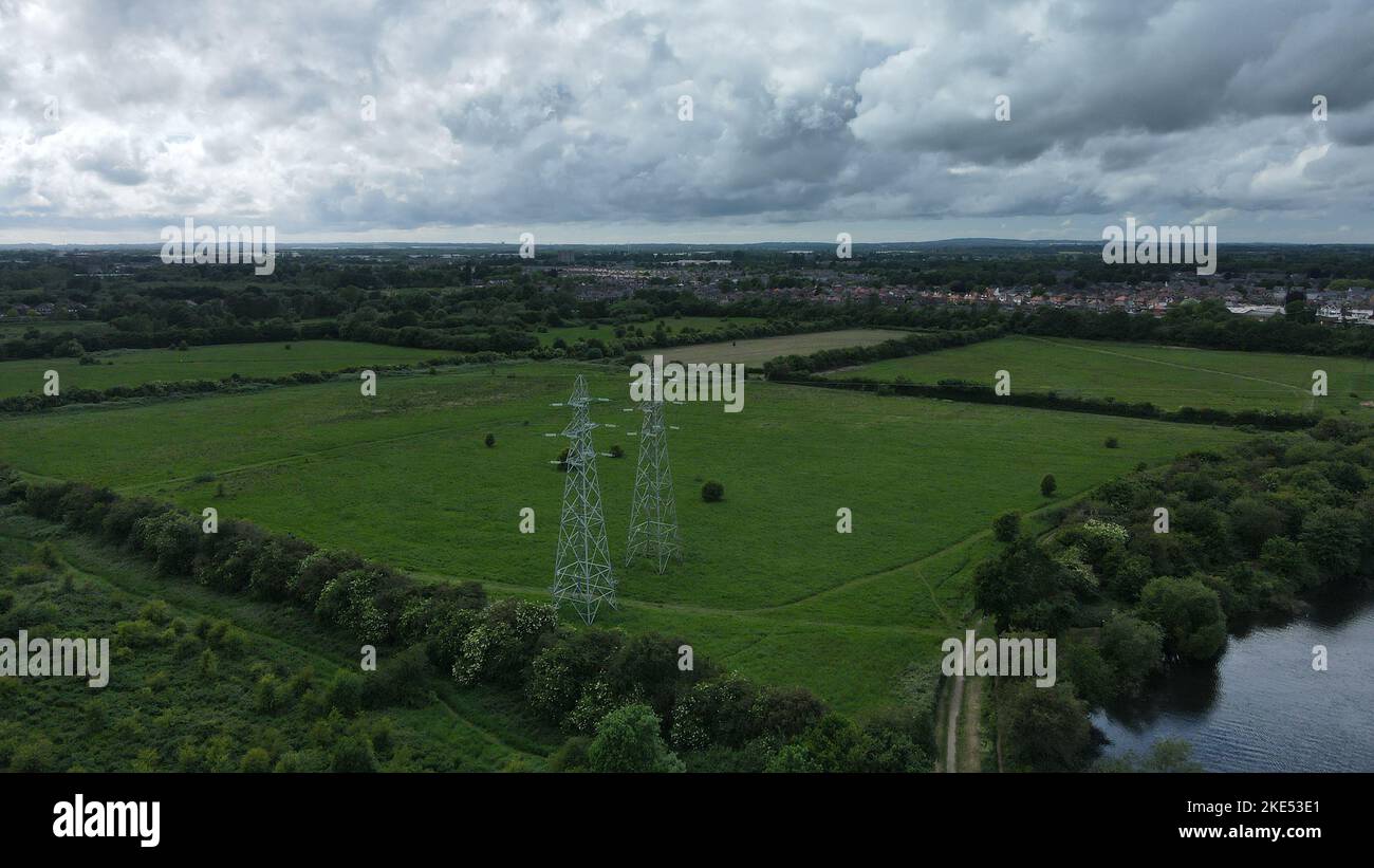 An aerial view of tension power lines and pylon meadowland with suburbs ...