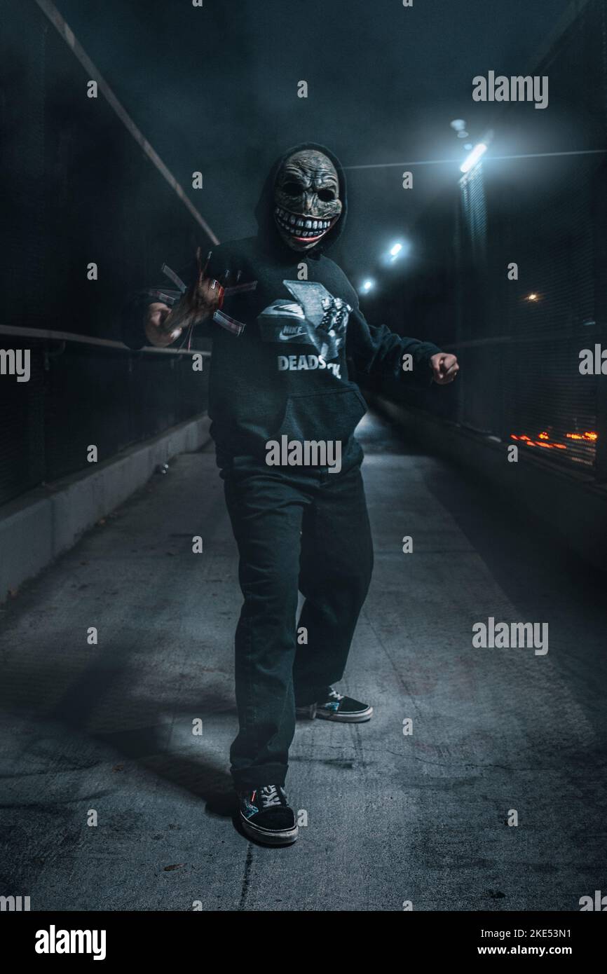 Standing alone in a mask in the dark Stock Photo - Alamy