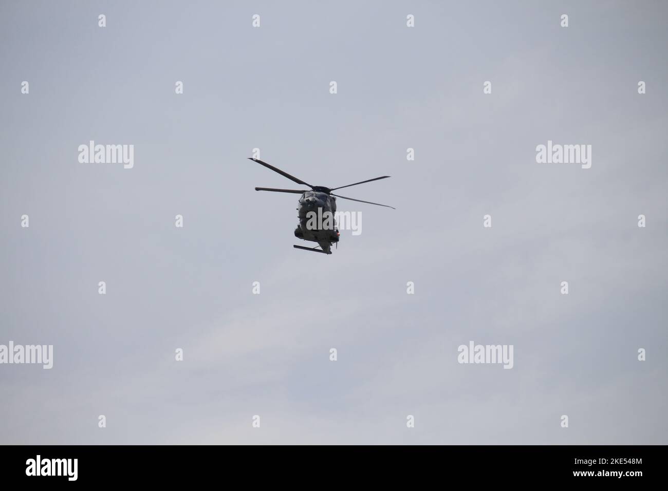 A helicopter captured flying high in the grey sky Stock Photo - Alamy