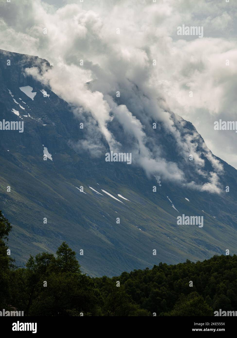 A vertical shot of a mountain slope covered in heavy clouds, perfect ...