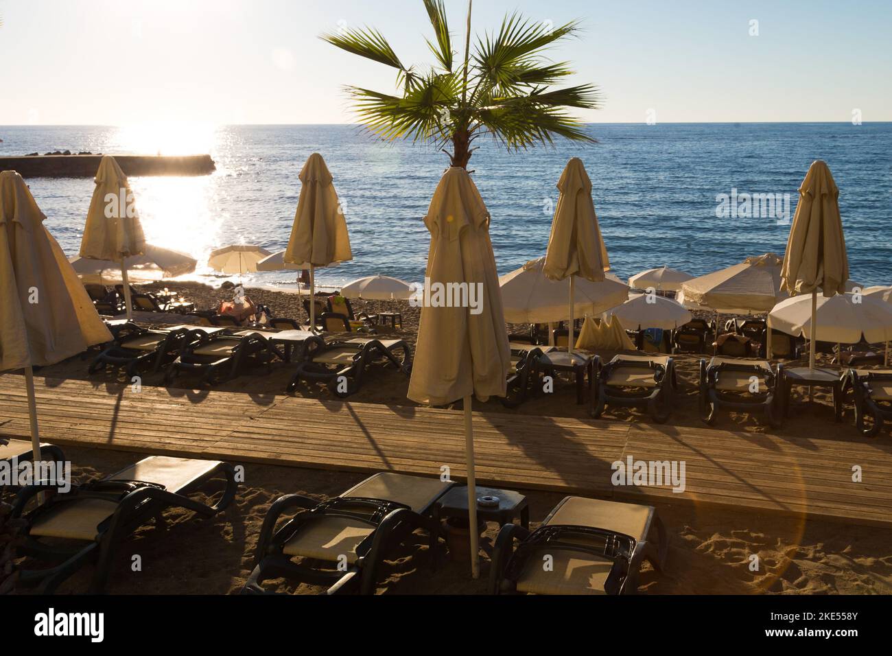 Sandy beach with umbrellas sunbeds at sunset Stock Photo - Alamy