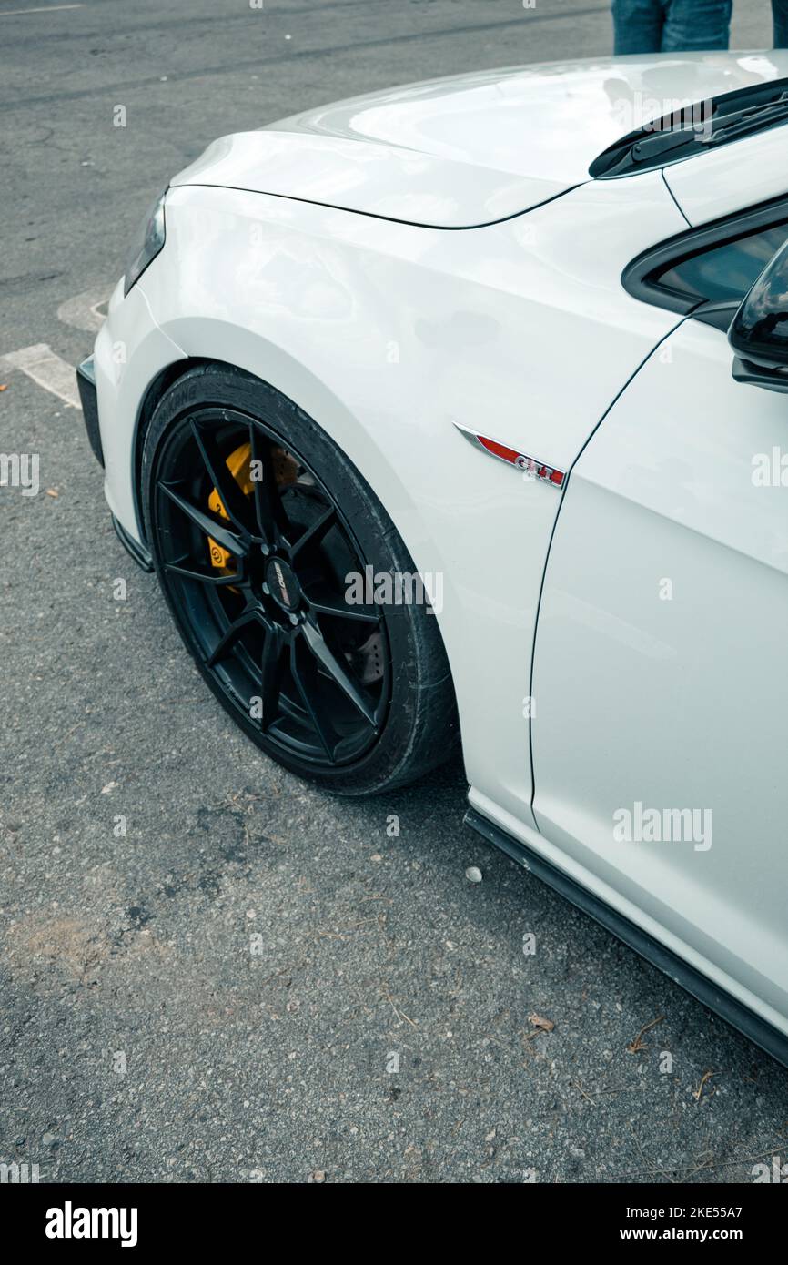 A vertical shot of the front left wheel of a modern white car parked on ...