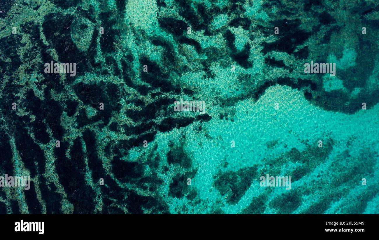 Caribbean green sea from above with black rocks under water. a ...