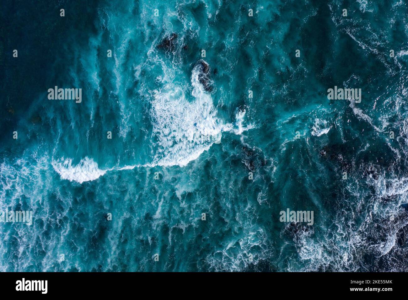 the turquoise ocean breaks in white foamy waves on the black beach ...