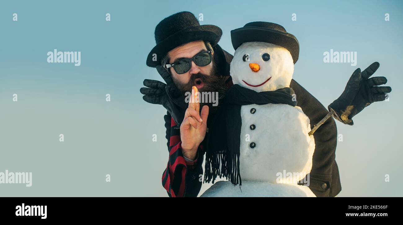 Funny winter snowman in hat play with snowman outdoor. Man with snowman ...