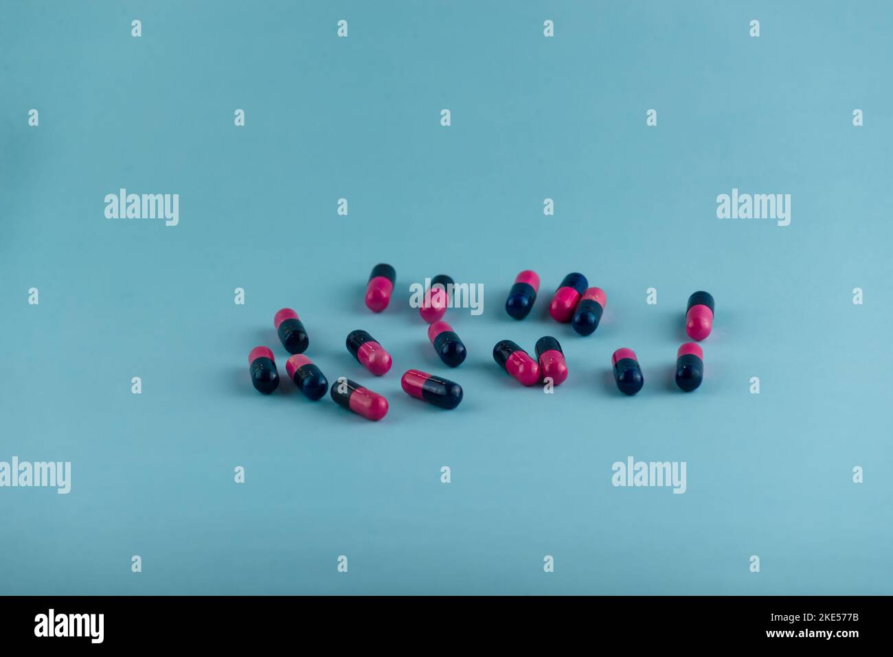 Simple pile of pink and black pills. Medicines, pills stacked on blue ...