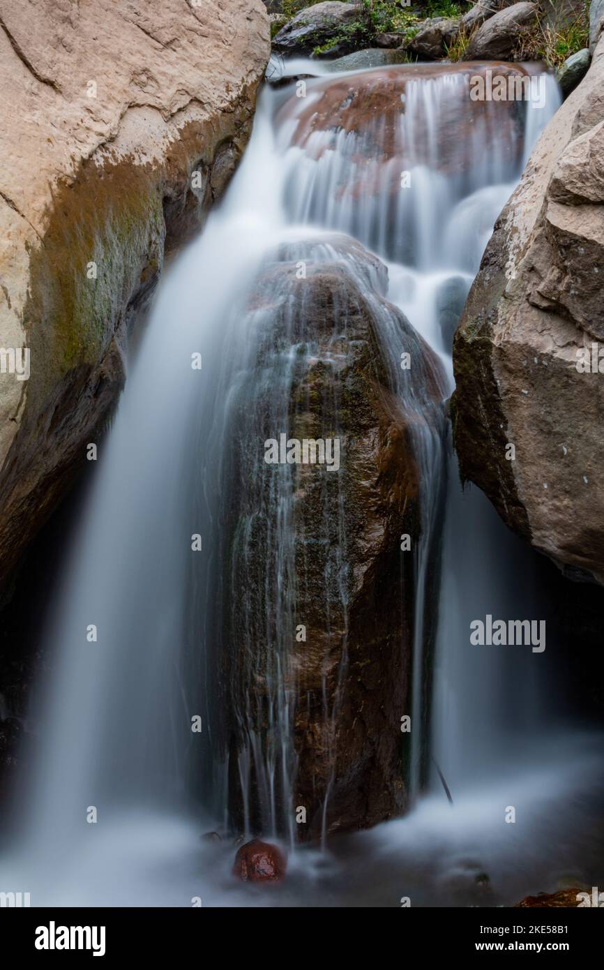 A long exposure shot of a small waterfall full of rocks in the daylight ...