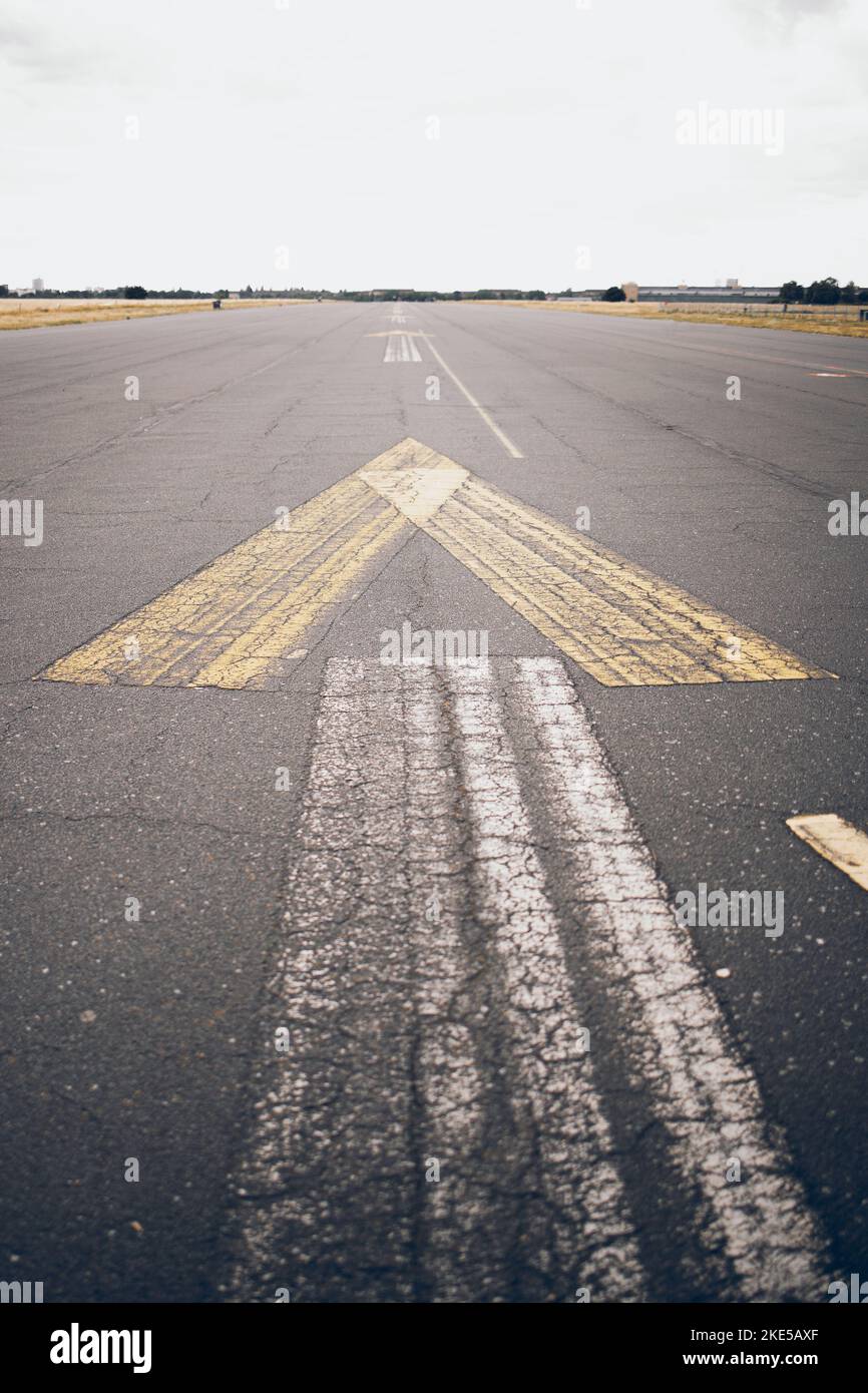 A vertical closeup of an arrow road street marking on an asphalt road ...