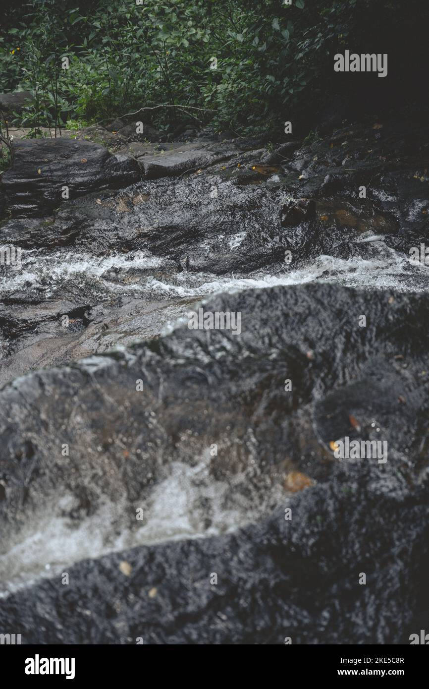 A river water flowing on hug rocks Stock Photo - Alamy