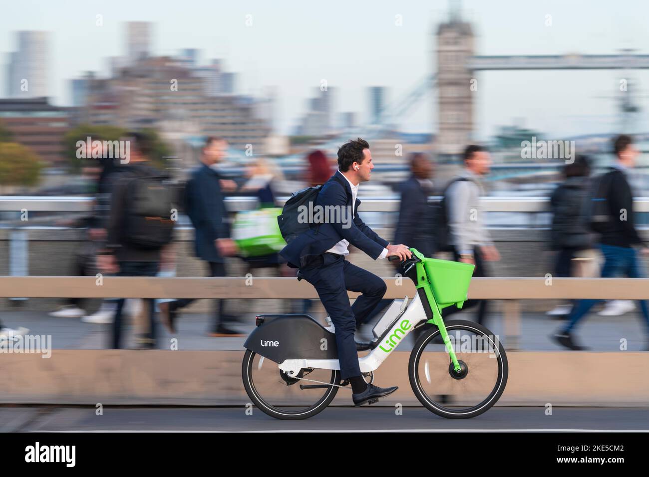 A man commuting on a Lime electric hire bike across London Bridge ...