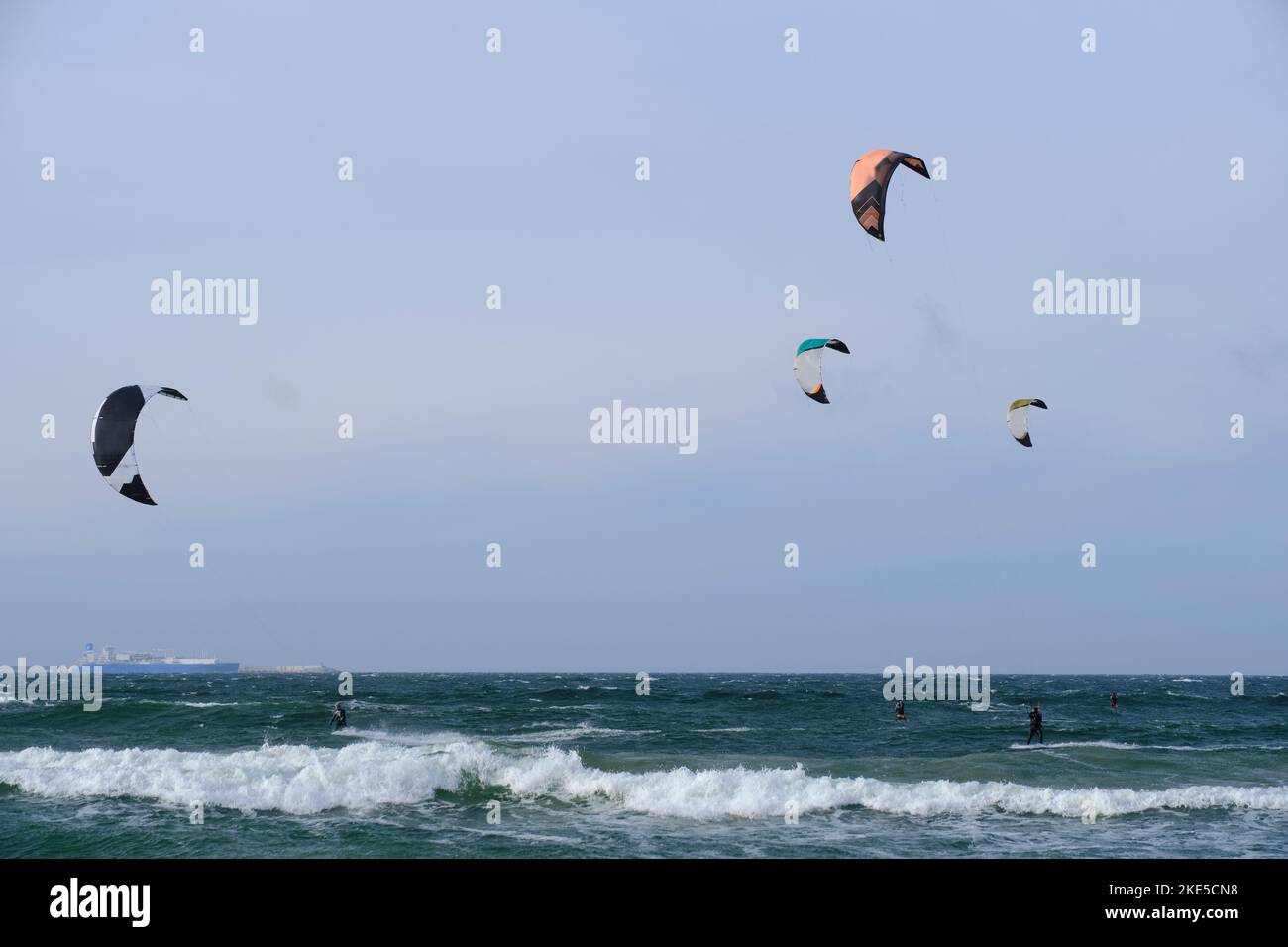 Kitesurfing, riding board waves during storm holding to flying kite ...