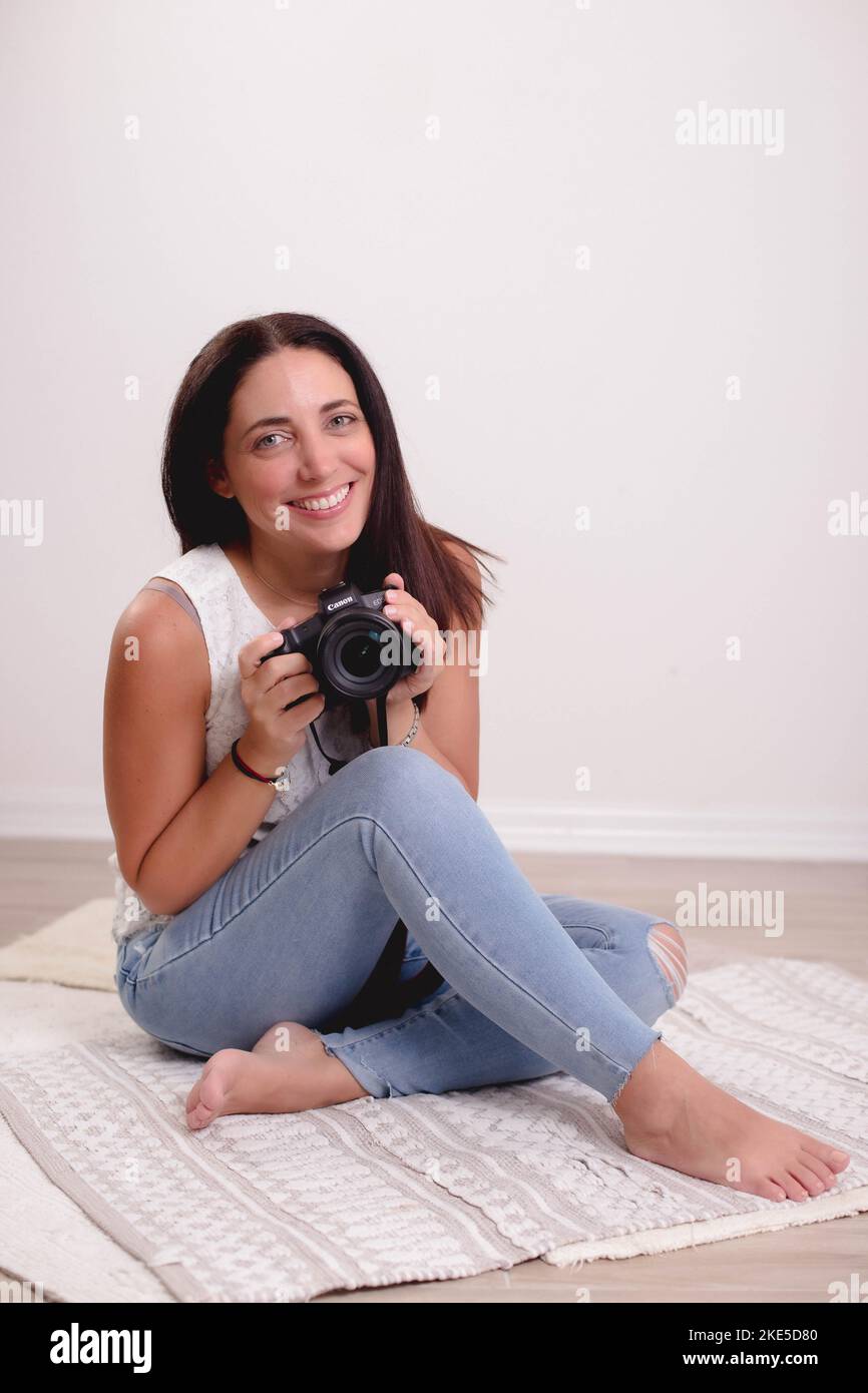 A vertical portrait of a caucasian female photographer holding a canon ...