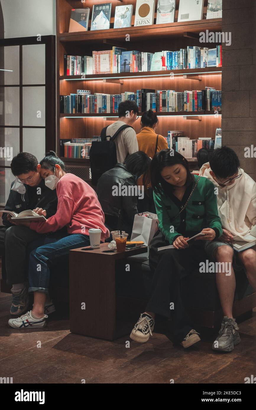 A vertical of people reading and browsing in a Japanese bookshop ...