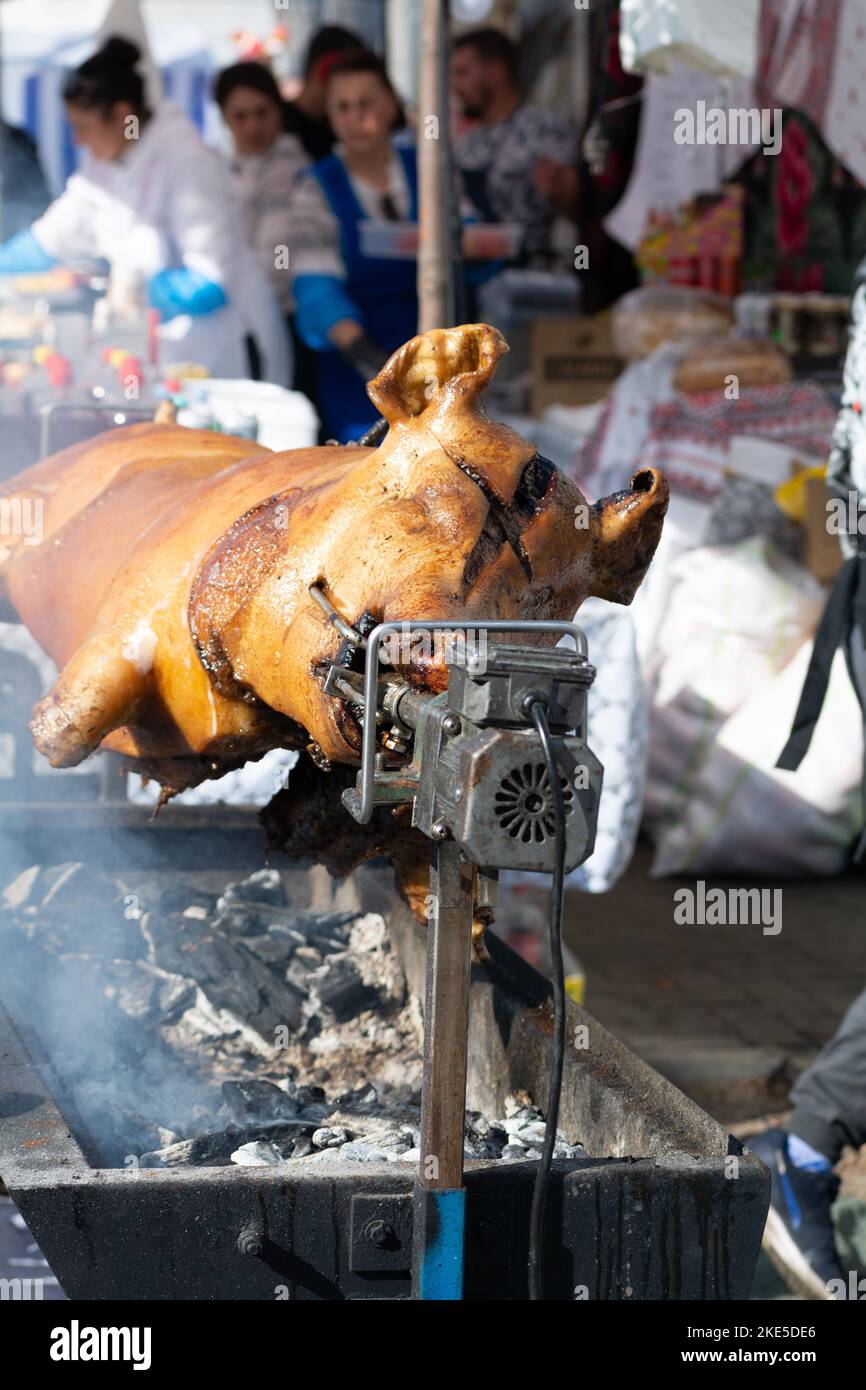 Piglet on a spit. Grilled pig at the street food festival. Roasted pig ...