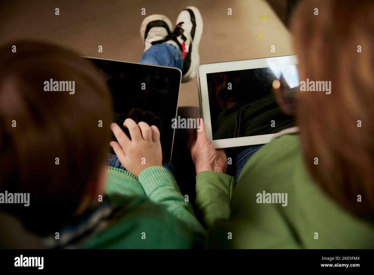Back view of grandmother and grandson spending time together, using ...