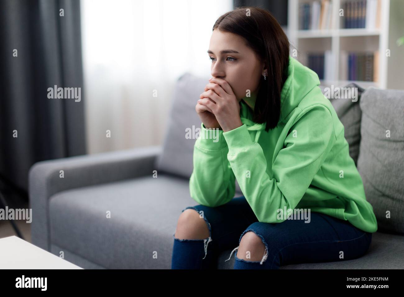 Worried woman on couch Stock Photo - Alamy