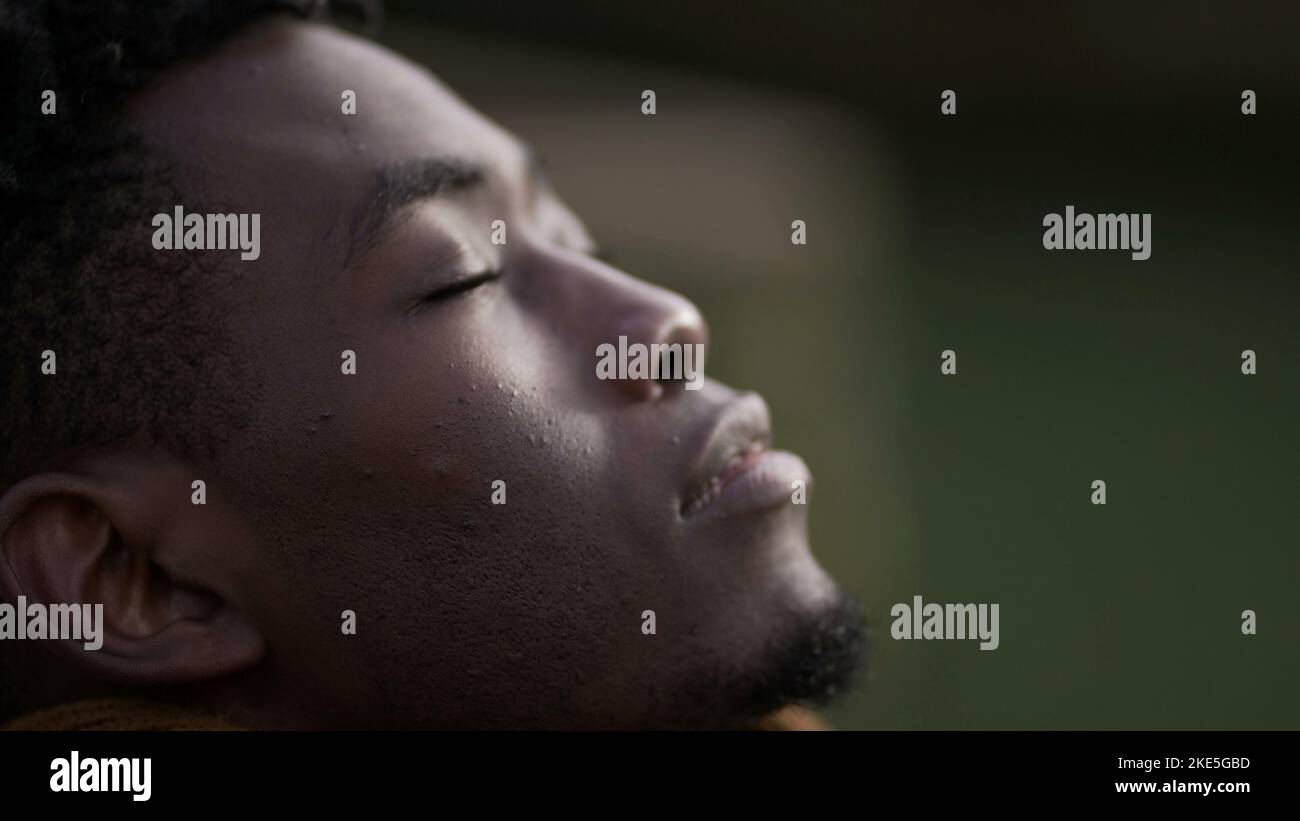 Black man taking a deep breath closing eyes and meditating outside eyes ...