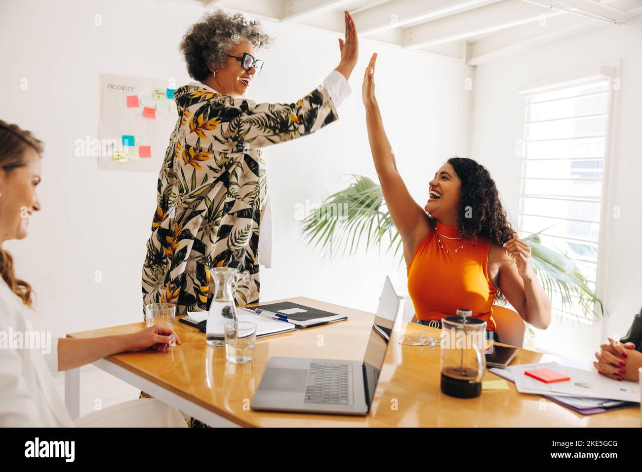 Successful businesswomen high fiving each other during a meeting in a ...