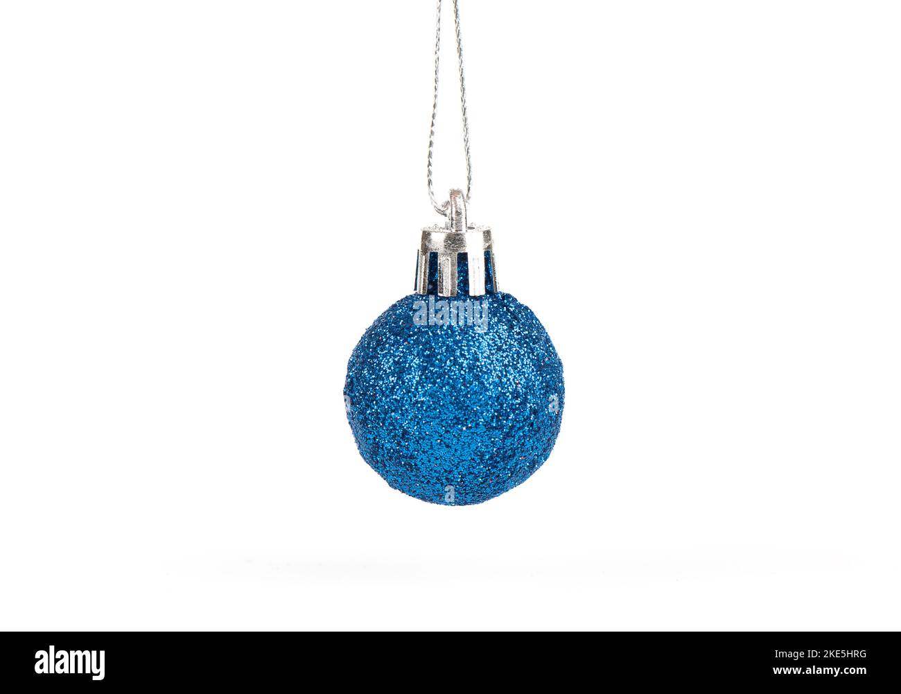 One blue ball Christmas tree toy hangs over a white background. Copy ...
