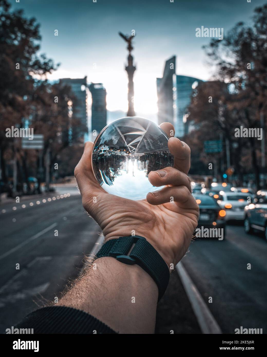 A handheld crystal ball on a busy main street in with huge skyscrapers ...
