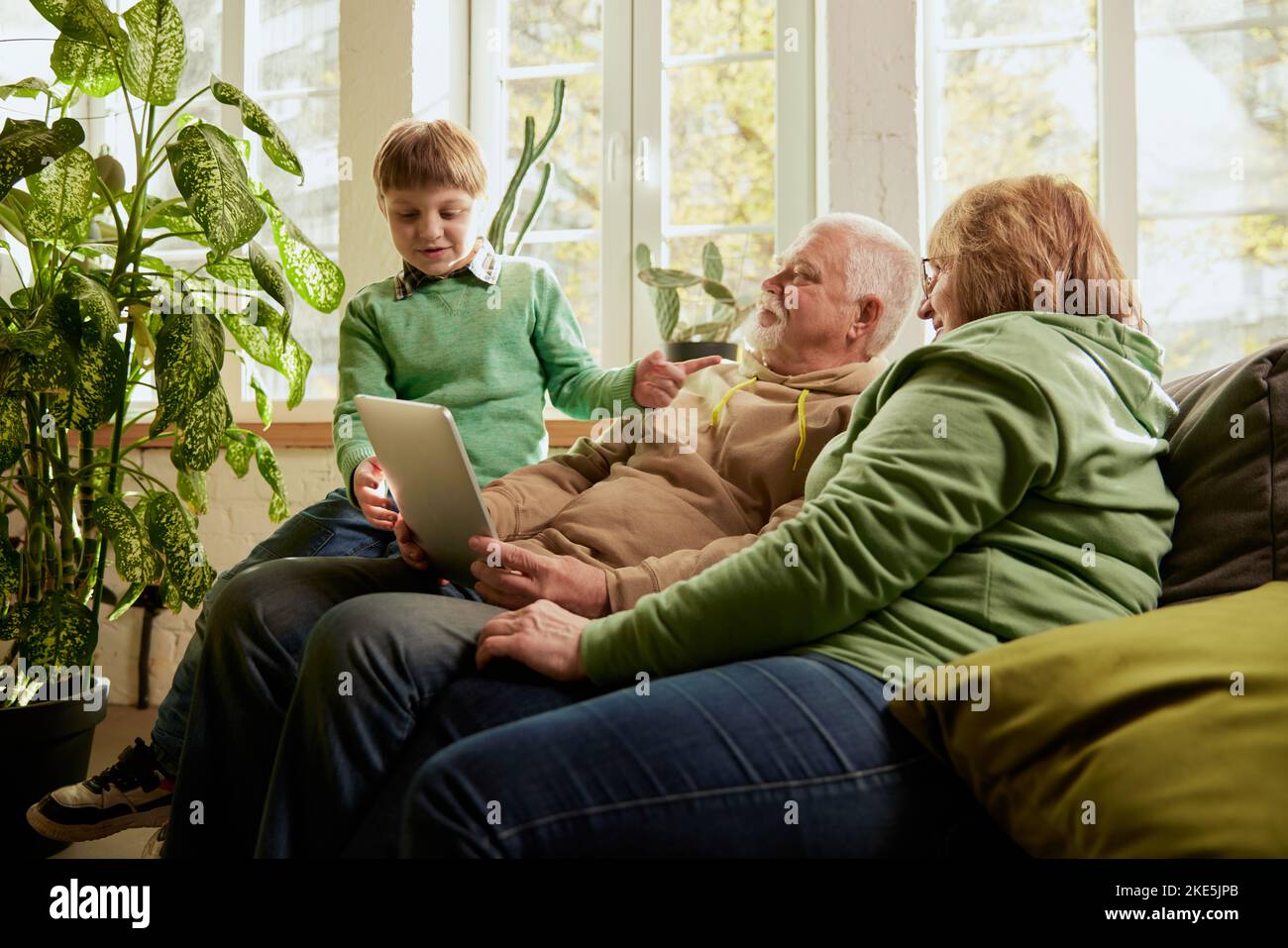 Happy friendly family, grandparent and grandson sitting on sofa and ...