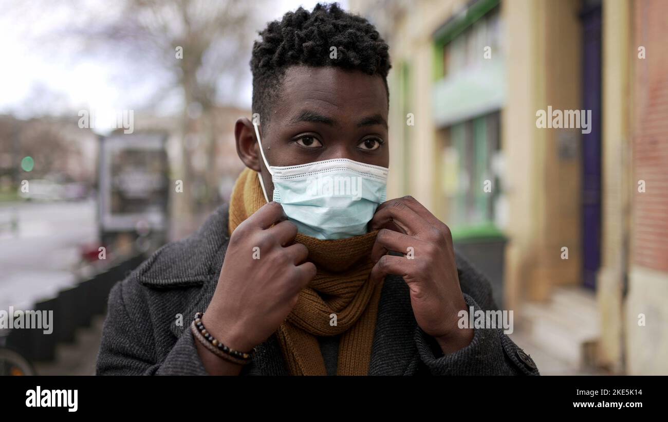 Black man putting covid face mask while walking in city outside in the ...