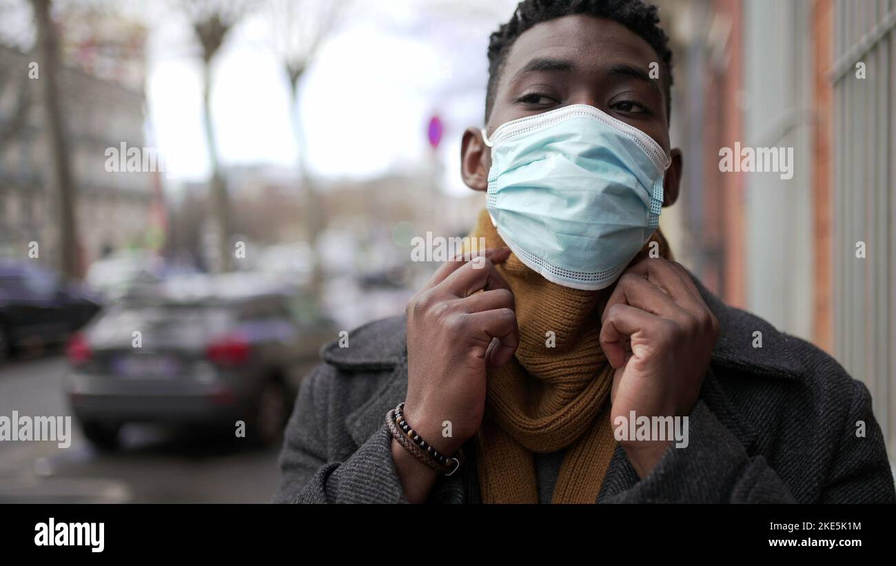 Black man putting covid face mask while walking in city outside in the ...
