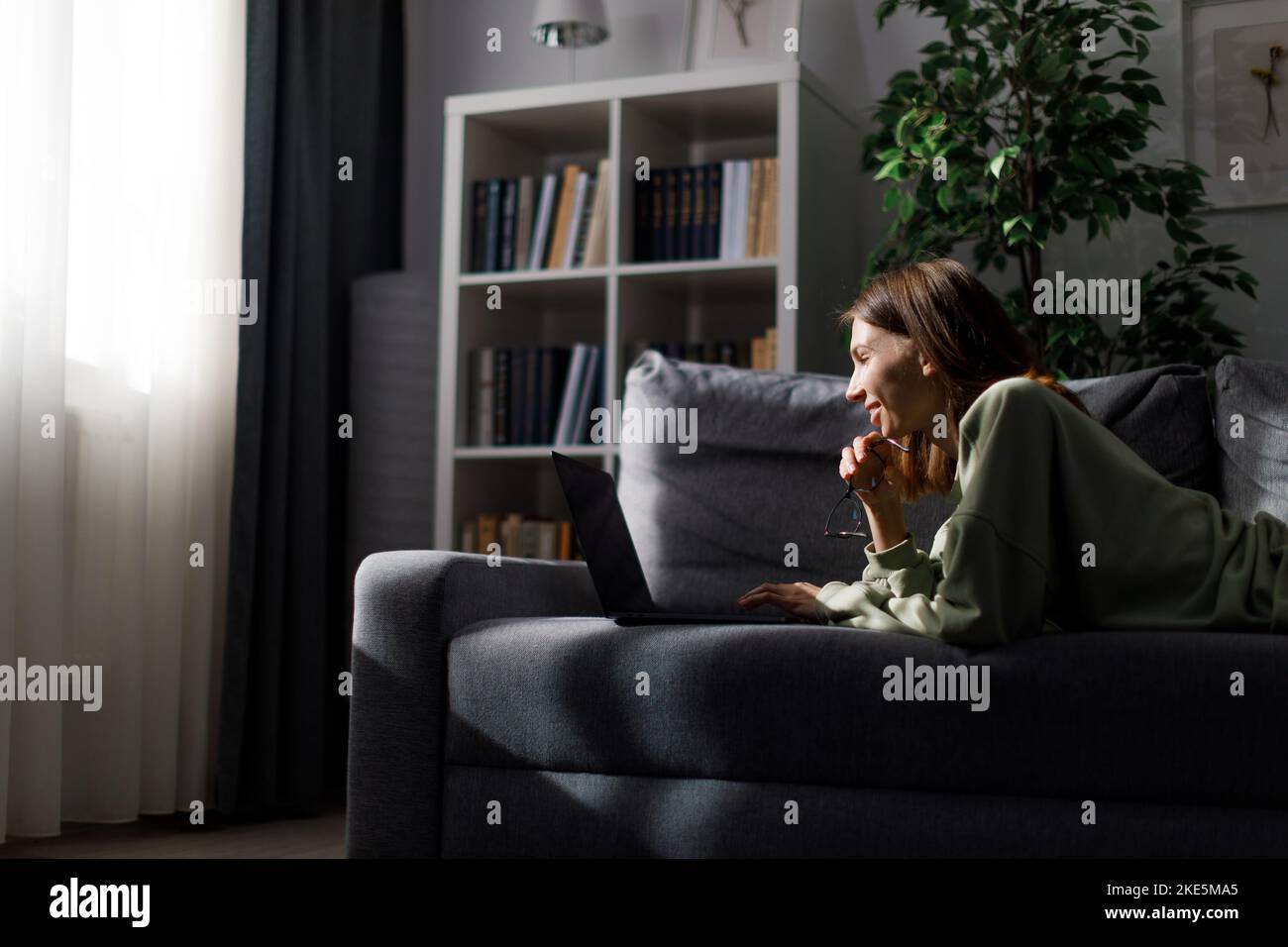 Woman resting on sofa with laptop Stock Photo - Alamy