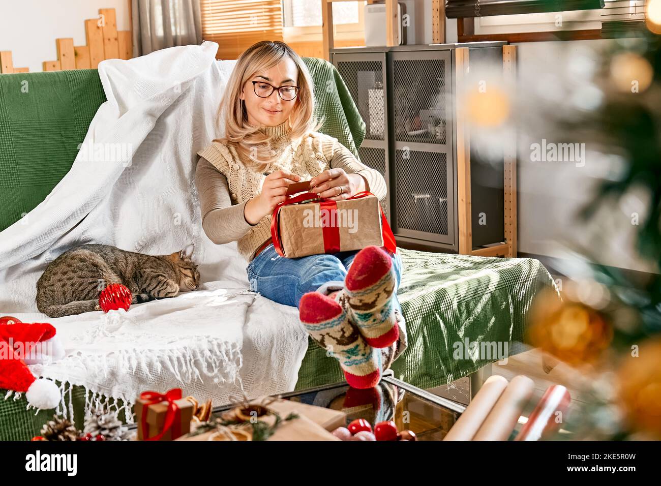 Wrapping christmas gifts. Blond woman wrapping present in recycled card ...