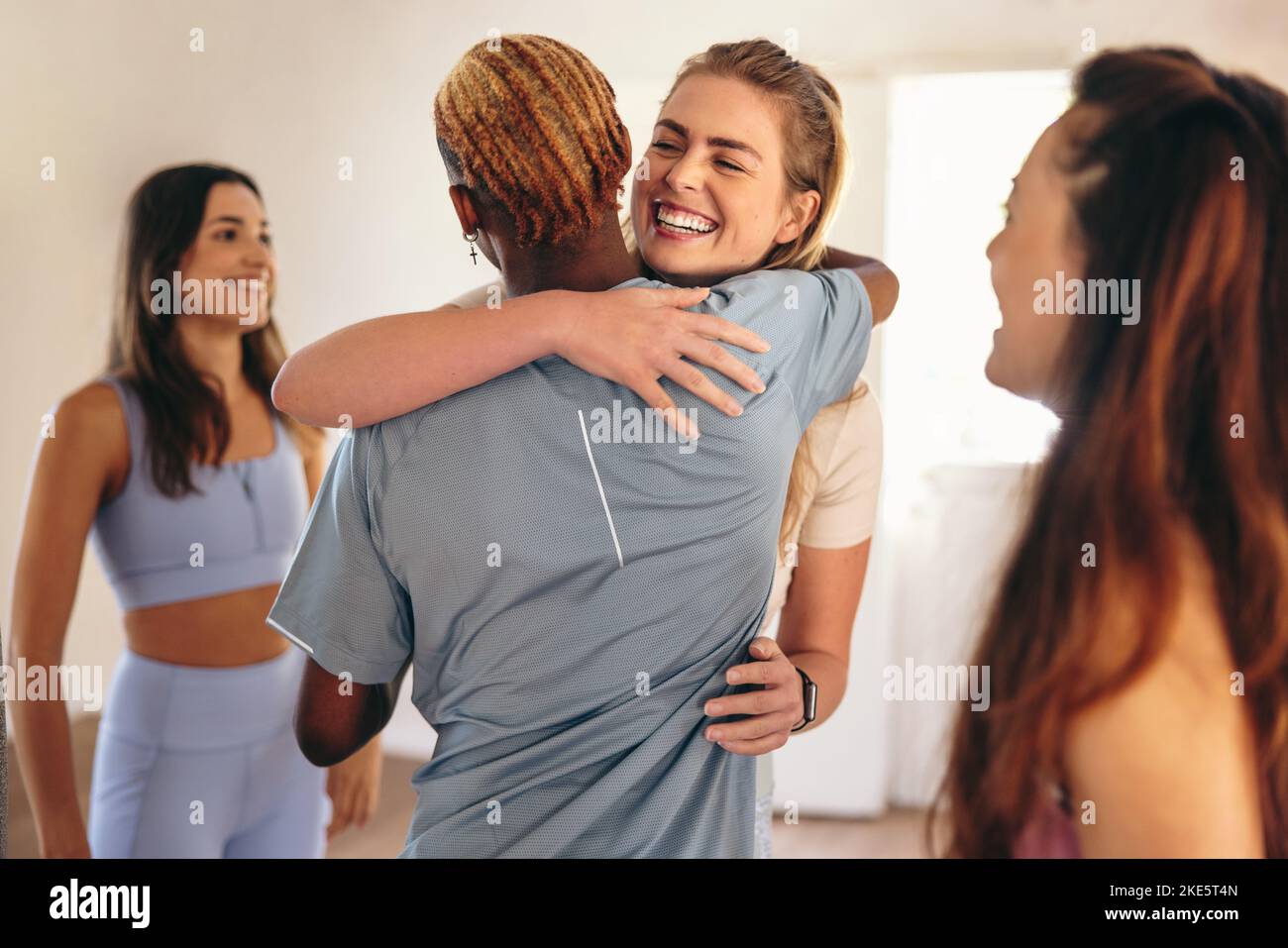Two happy friends greeting each other with a hug in a yoga studio ...