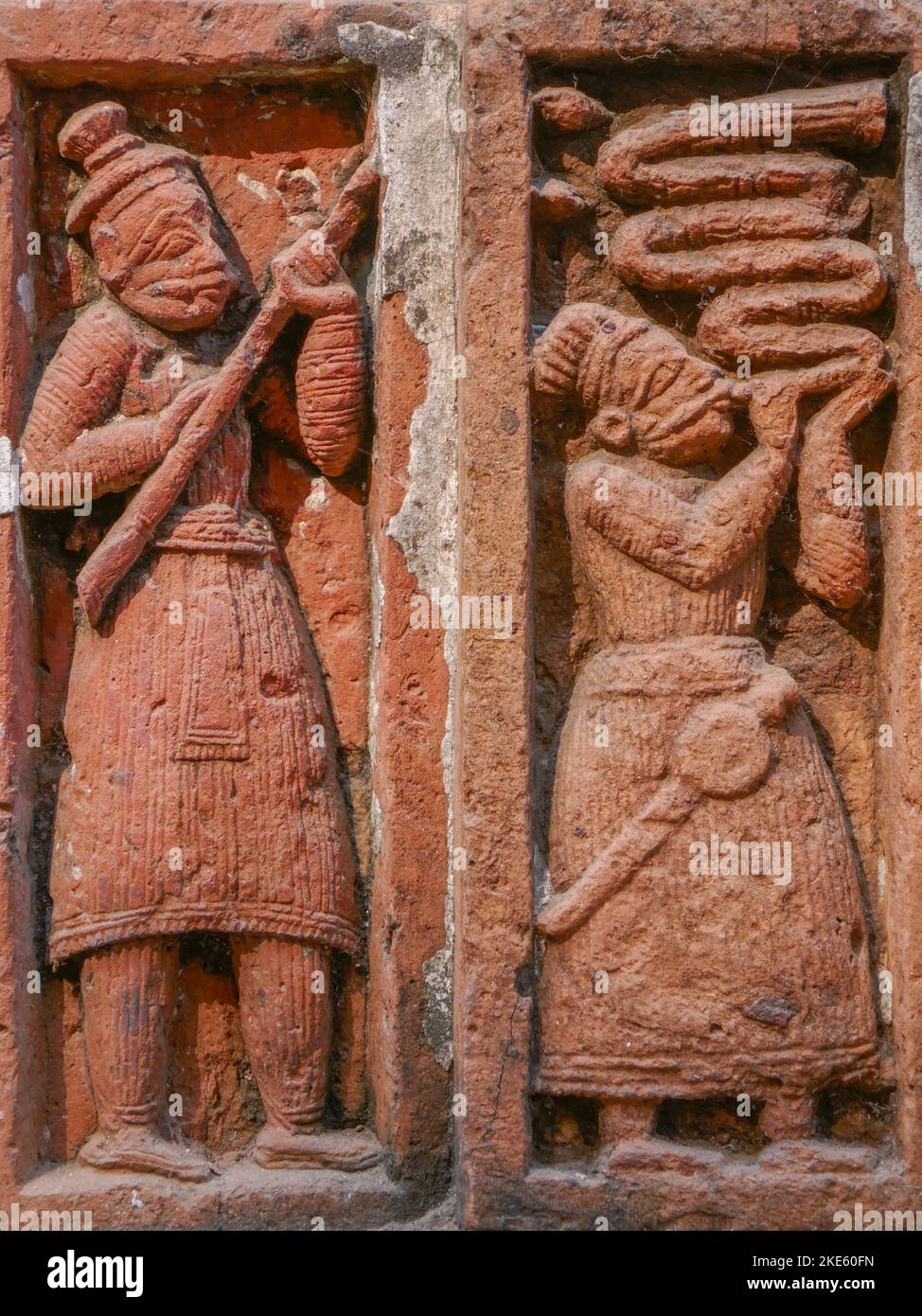 Closeup of ancient terracotta carving scene of man blowing horn at ...