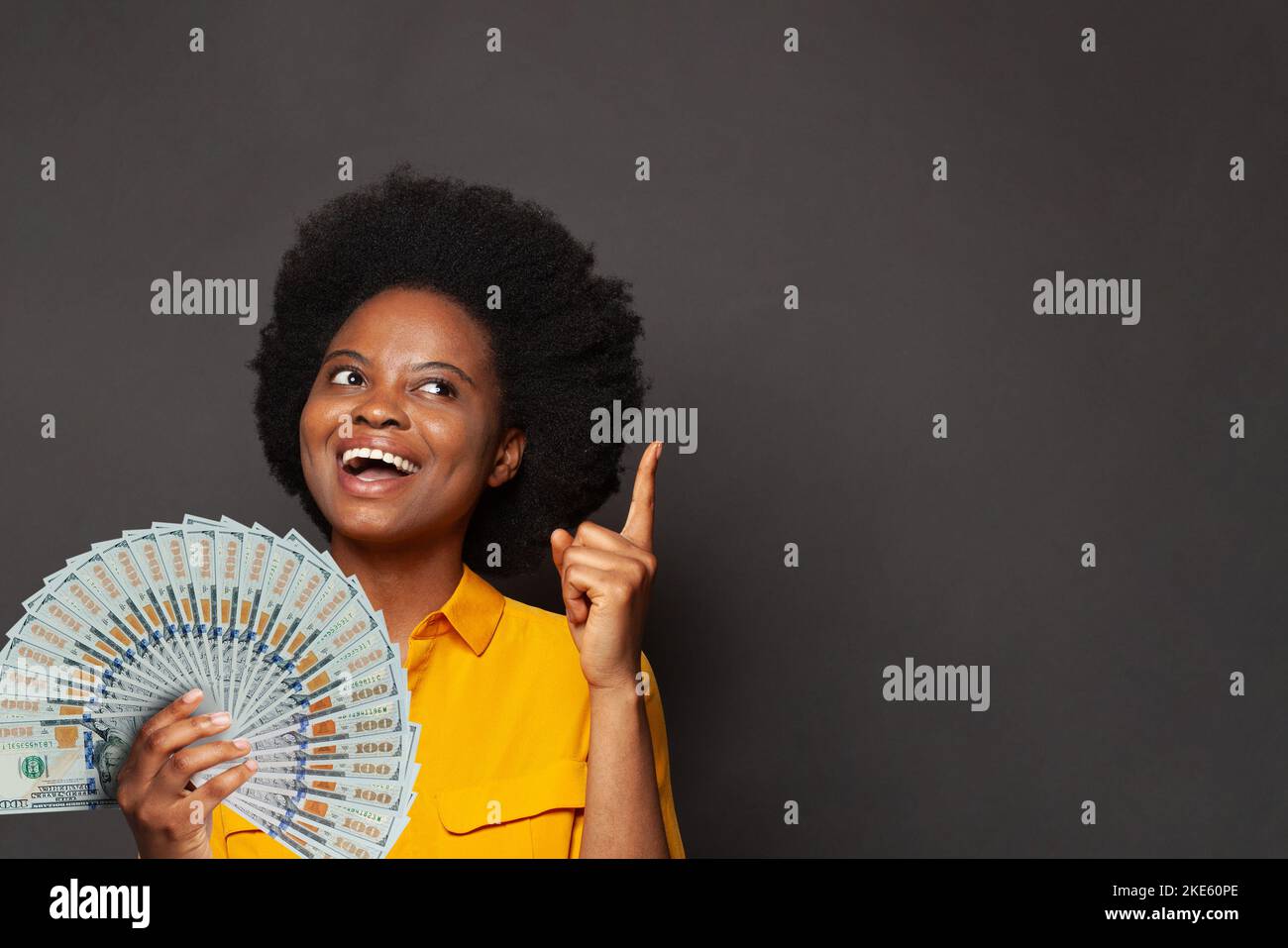 Cheerful exited african american woman shows up and holds fan of money ...