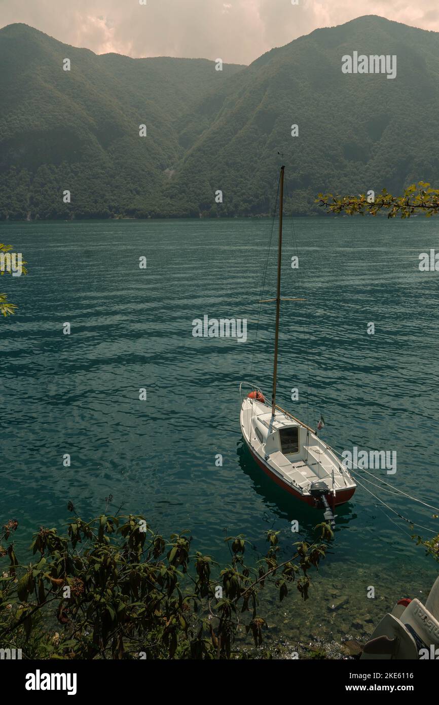 A vertical shot of a boat floating on the Lugano Lake surface in ...
