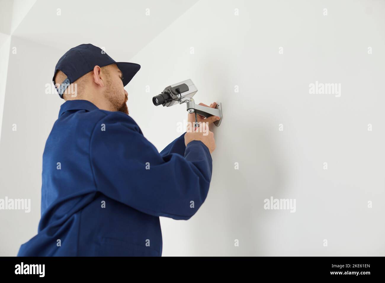 Man technician mount surveillance camera on wall Stock Photo - Alamy