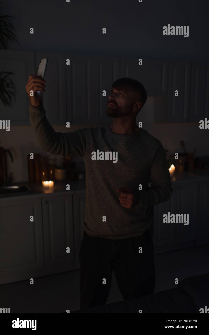man standing with smartphone in raised hand while searching for mobile ...