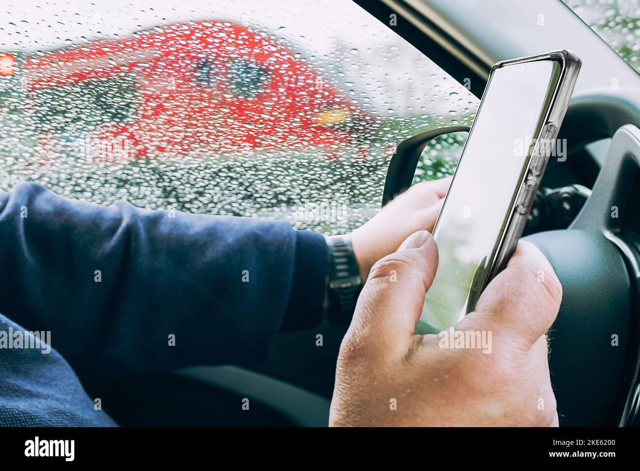 Driver holding a mobile phone in his hand while driving a car. The ...